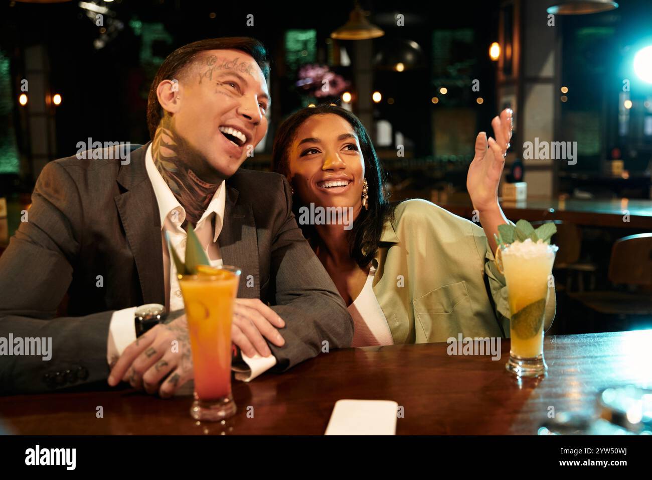 A young couple shares laughter and drinks during their night out at a ...