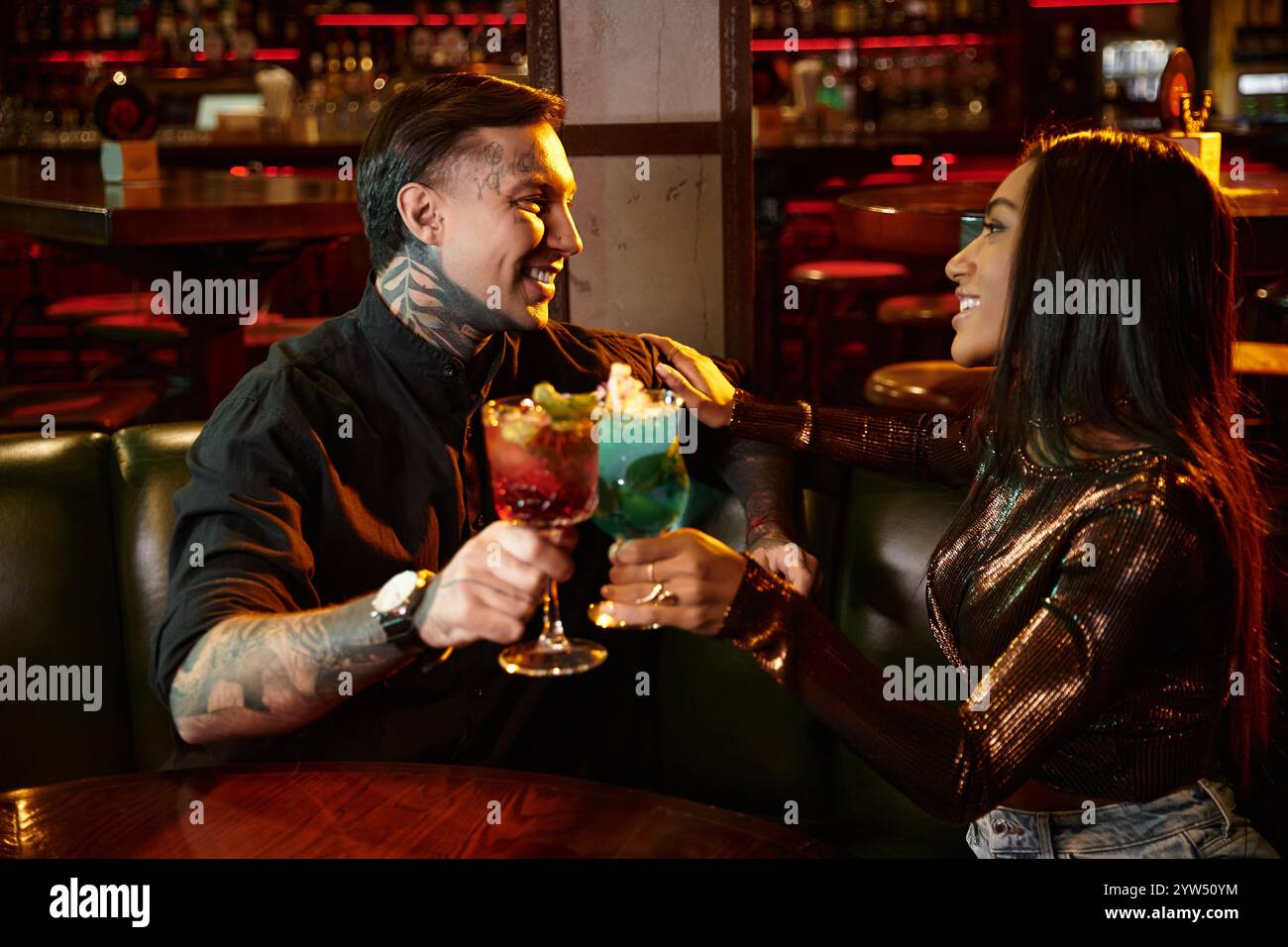 A young couple shares laughter and drinks at an upscale bar during a ...
