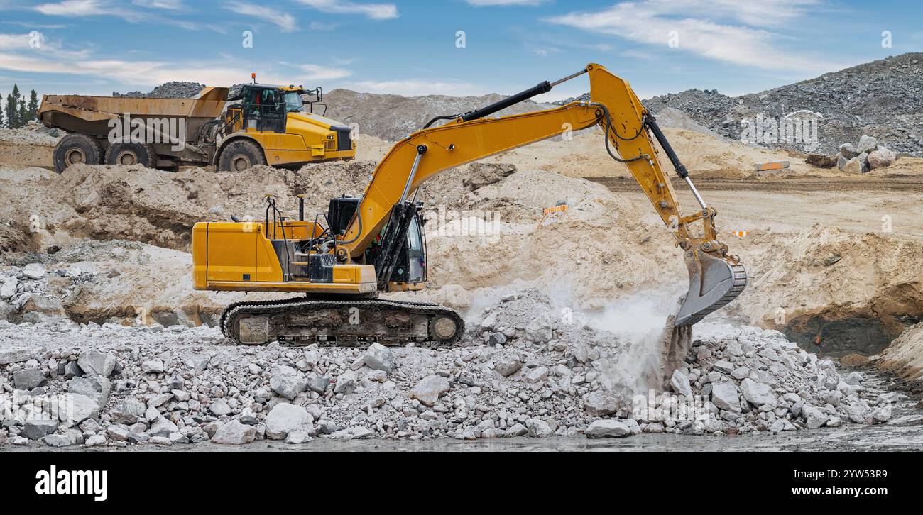 An excavator and a dumper working on a stone embankment Stock Photo - Alamy