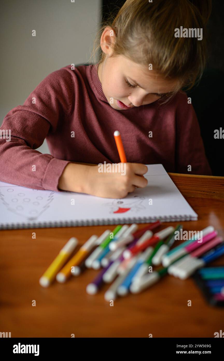 girl is sitting on the table she is studying painting and reading with ...