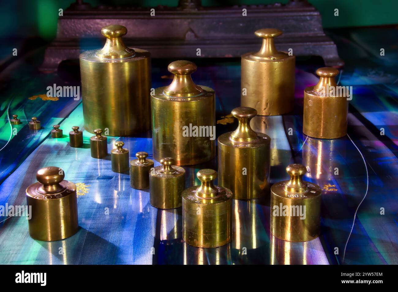 A set of vintage balance weights on a reflective coloured surface ...