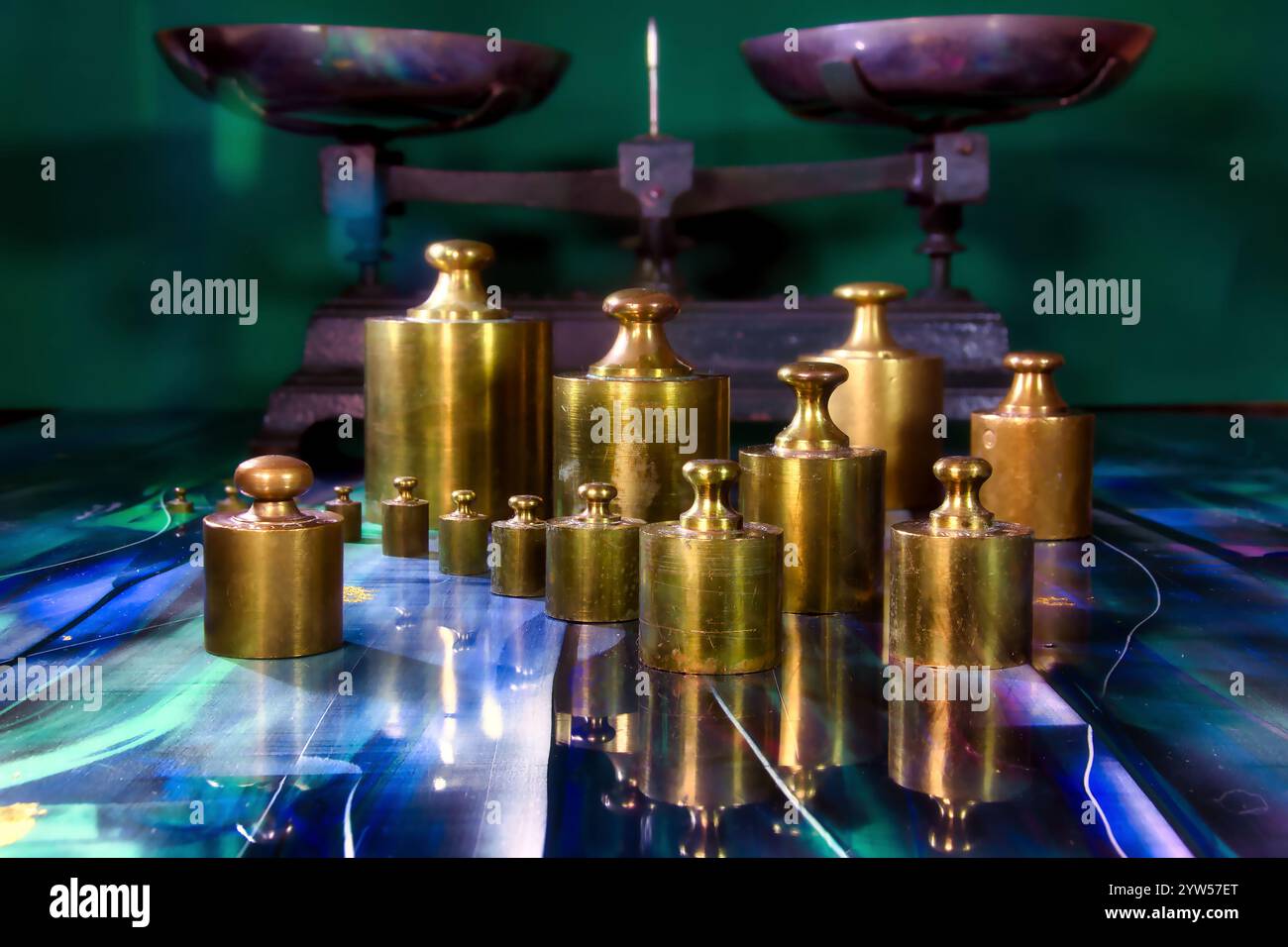 A set of vintage balance weights on a reflective coloured surface ...