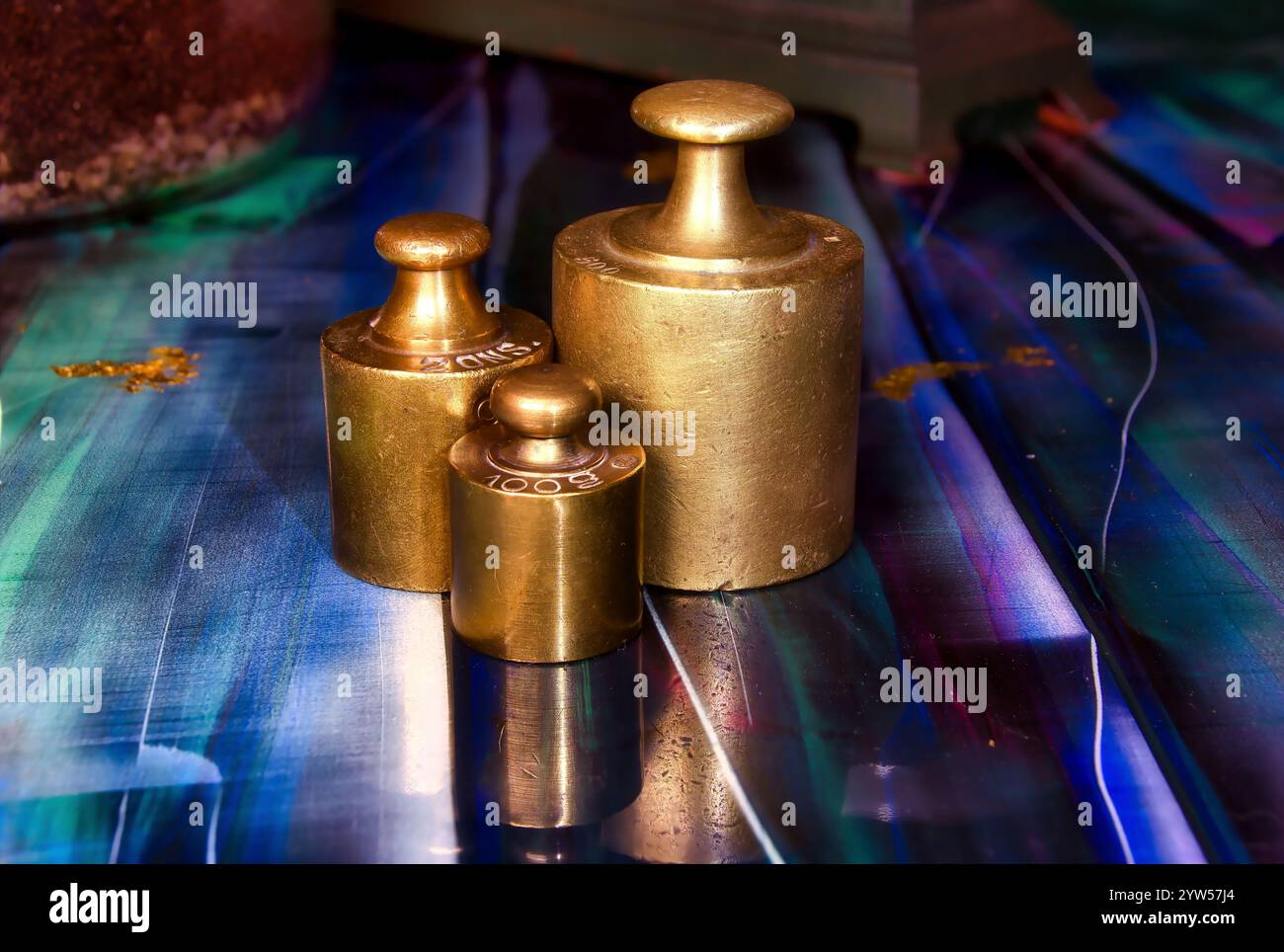 A set of vintage balance weights on a reflective coloured surface ...