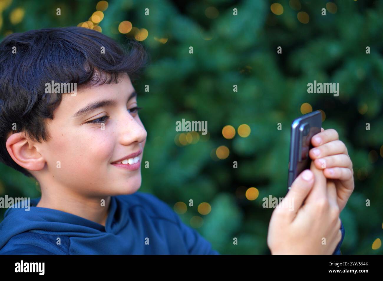 preteen boy making a video call, using his cell phone with a christmas ...