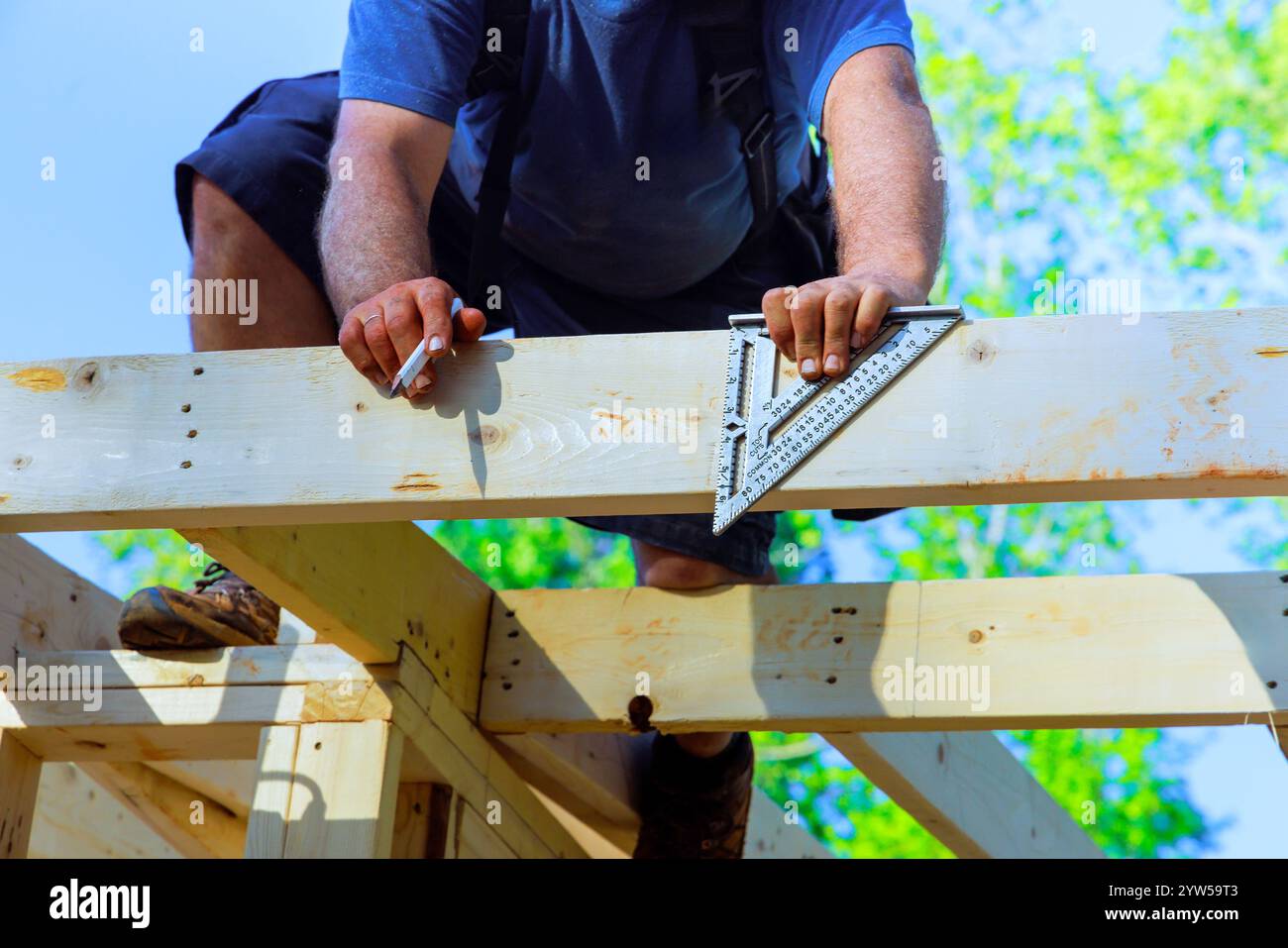 Carpenter uses square tool to measure wood frame beams while working on ...