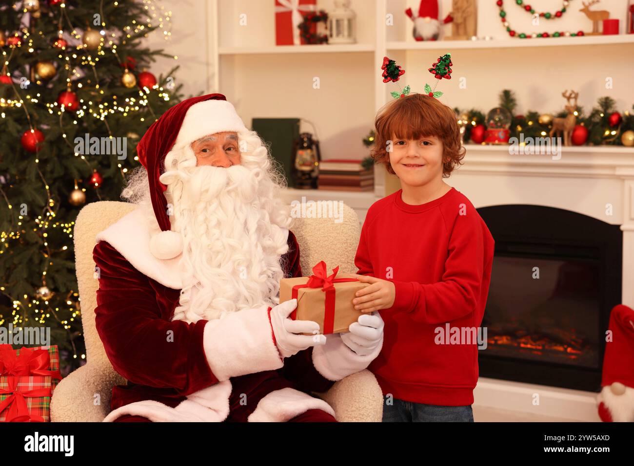 Christmas celebration. Santa Claus giving gift box to boy at home Stock ...