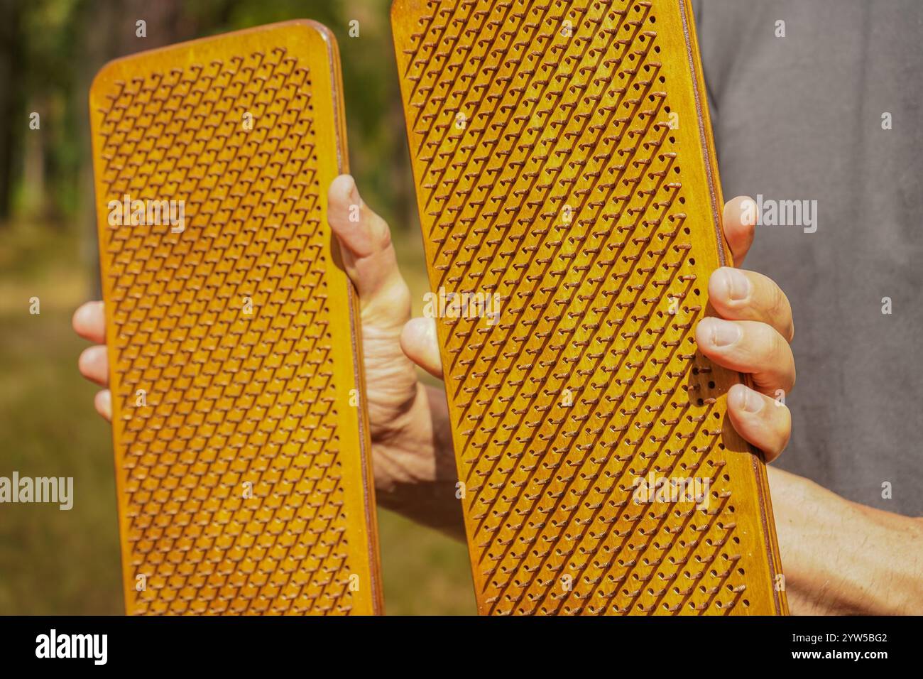 Close-up of a man holding two Sadhu boards, demonstrating an even row ...