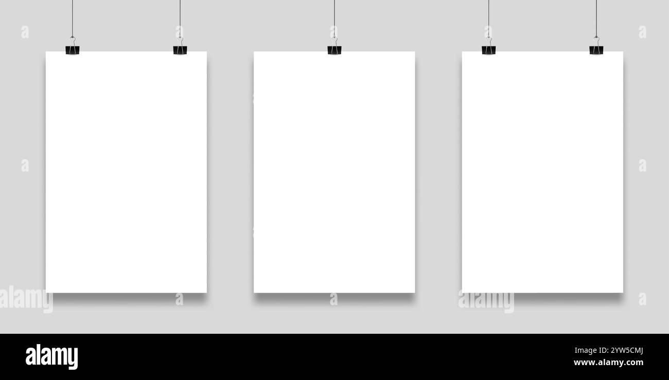 Three blank white papers are hanging on a gray wall, held by black ...