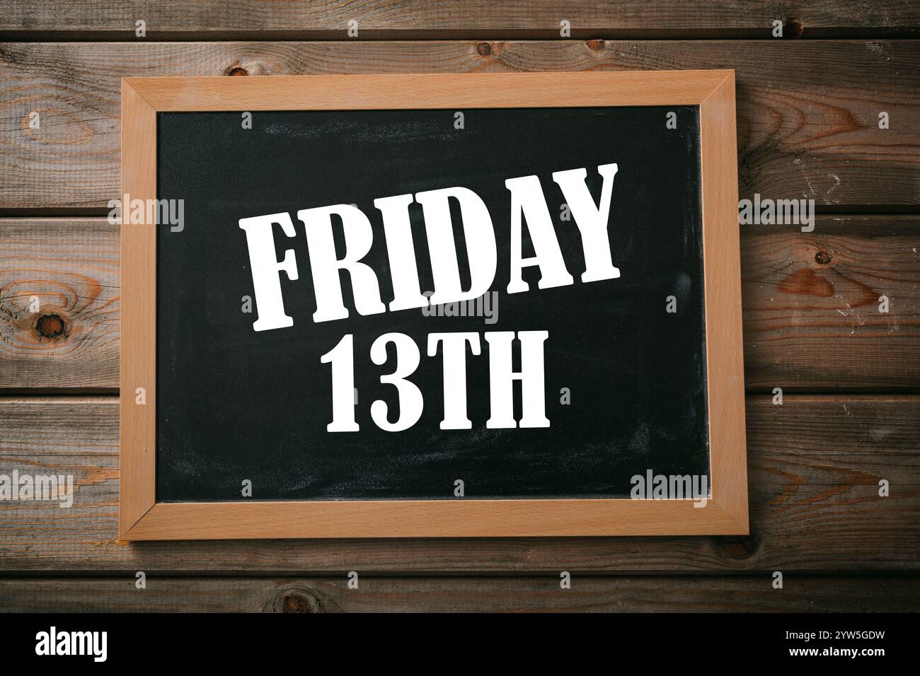 Friday the 13th text on a blackboard, wooden background. Bad luck date ...