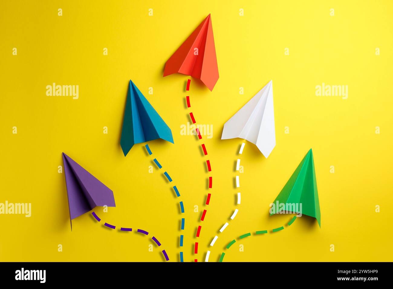 Colorful paper planes with flight paths on yellow background. Dashed ...