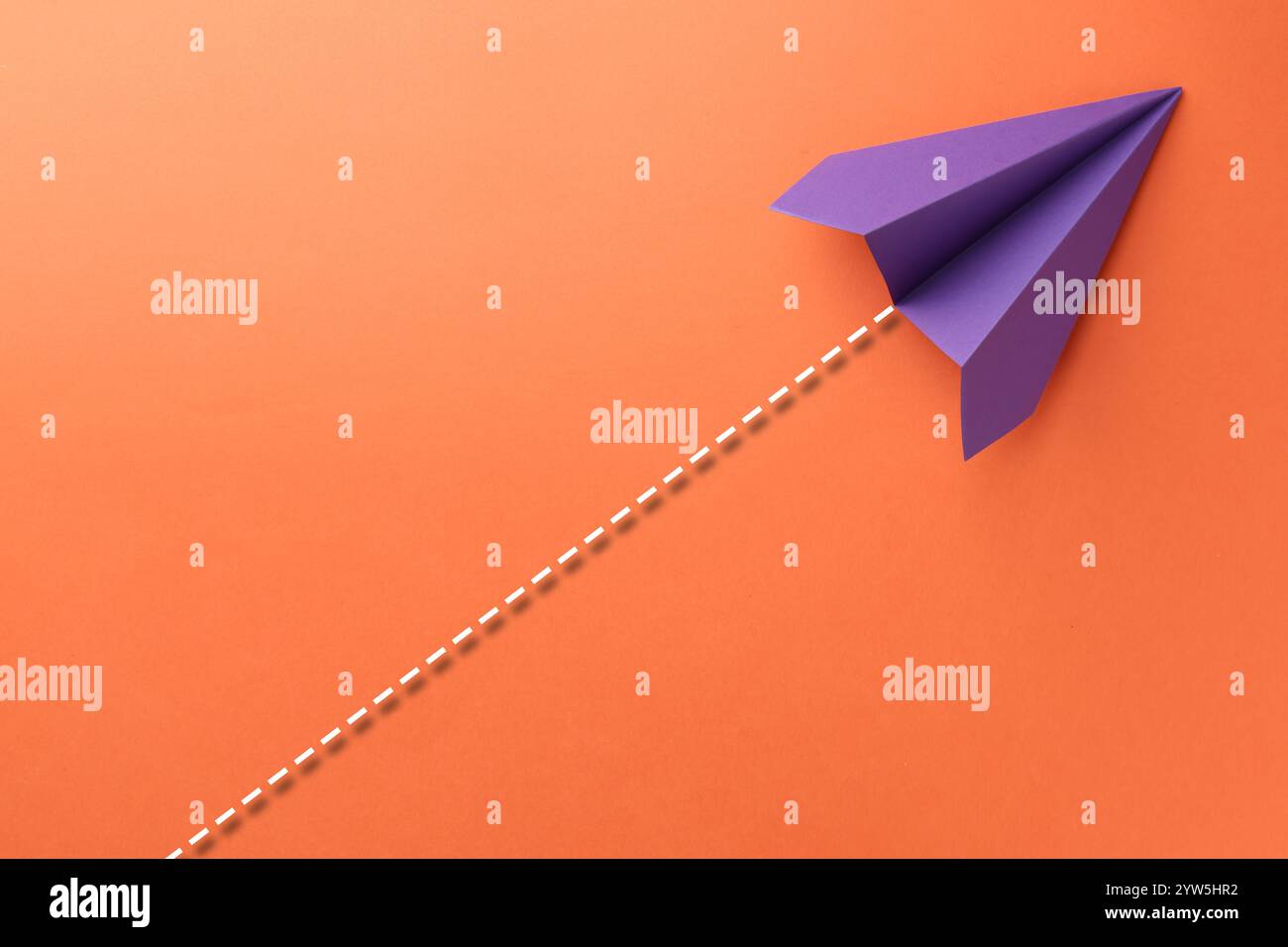 Purple paper plane with flight path on orange background. Dashed line ...