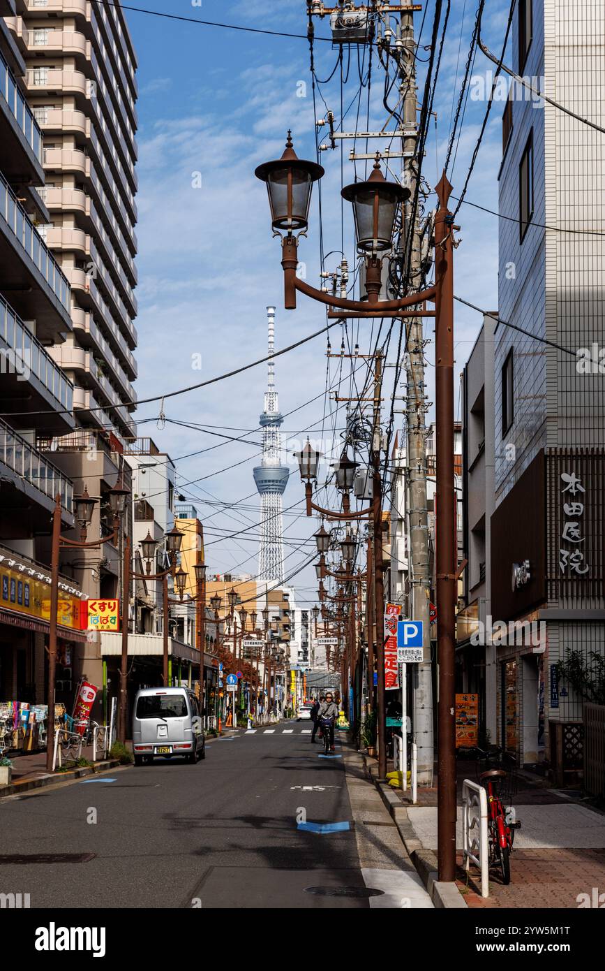 A bustling street in Tokyo, featuring numerous power lines and tall buildings, showcasing the ...