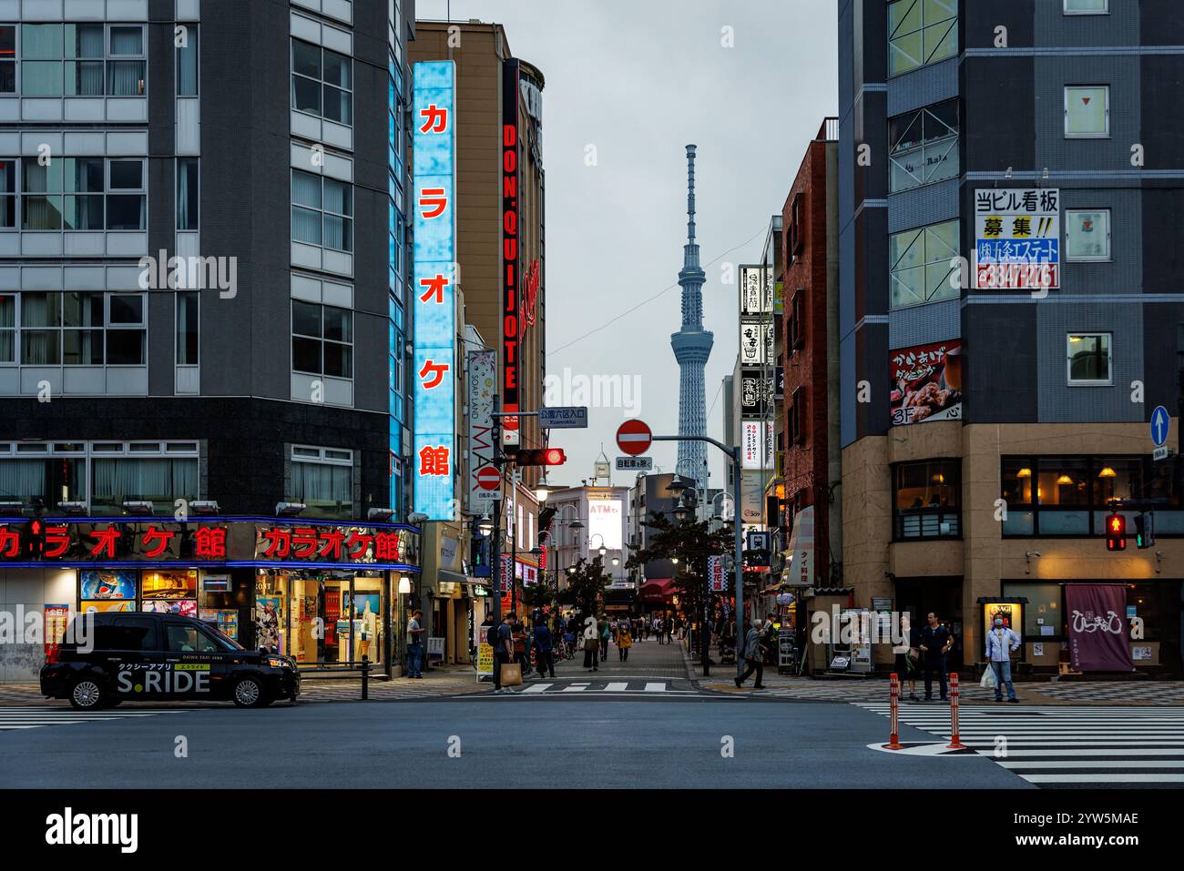 A bustling Tokyo street scene with bright neon signs and the iconic Tokyo Skytree in the ...