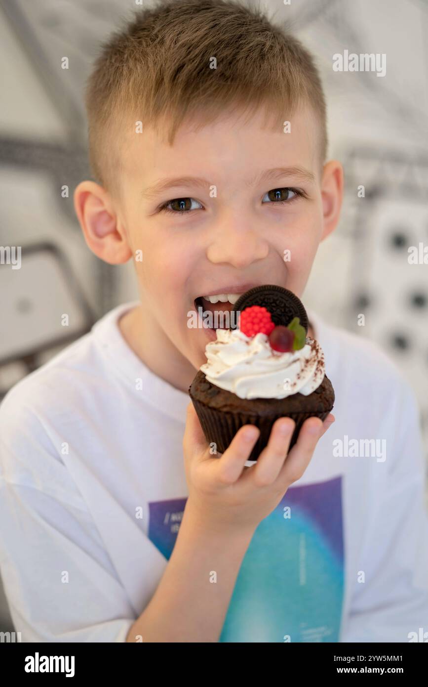 Joyful boy taking a bite of cake Stock Photo - Alamy