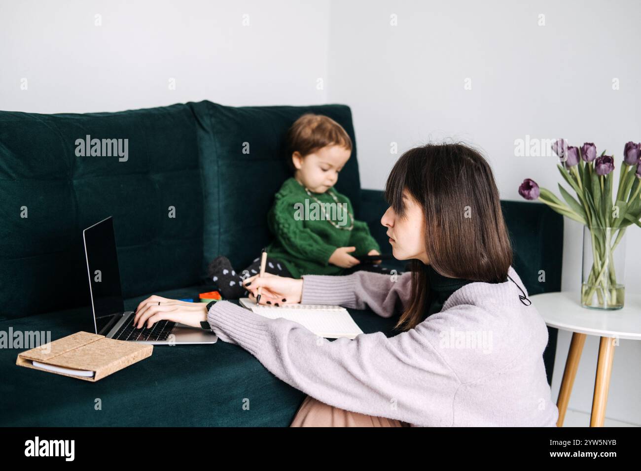 A mother manages work responsibilities while attending to her toddler ...