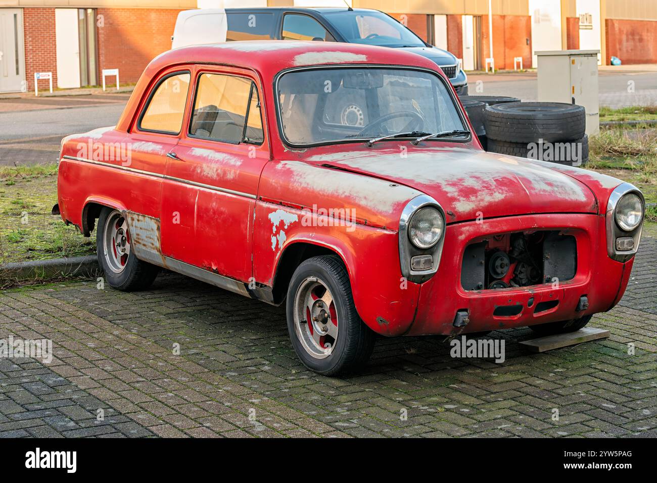red car wreck stands outside in a parking lot in an industrial area ...