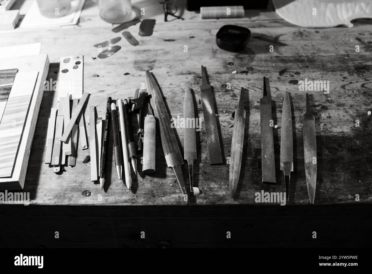 Files, rasps, pencils, and pieces of wood lay on a workbench in a ...