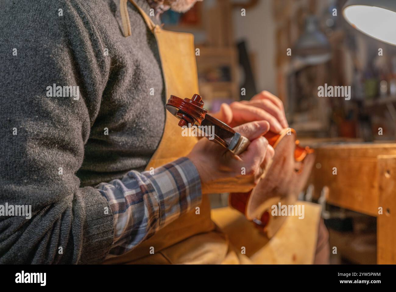 Luthier assembling a violin scroll in his workshop, using traditional ...
