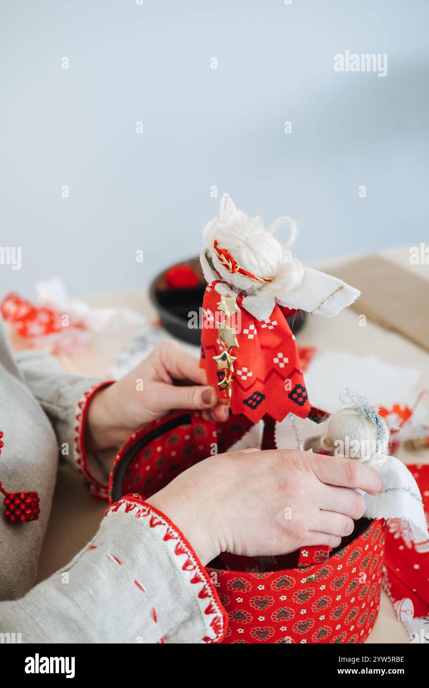 Crafting traditional folk doll with red and gold accents. Showcasing ...