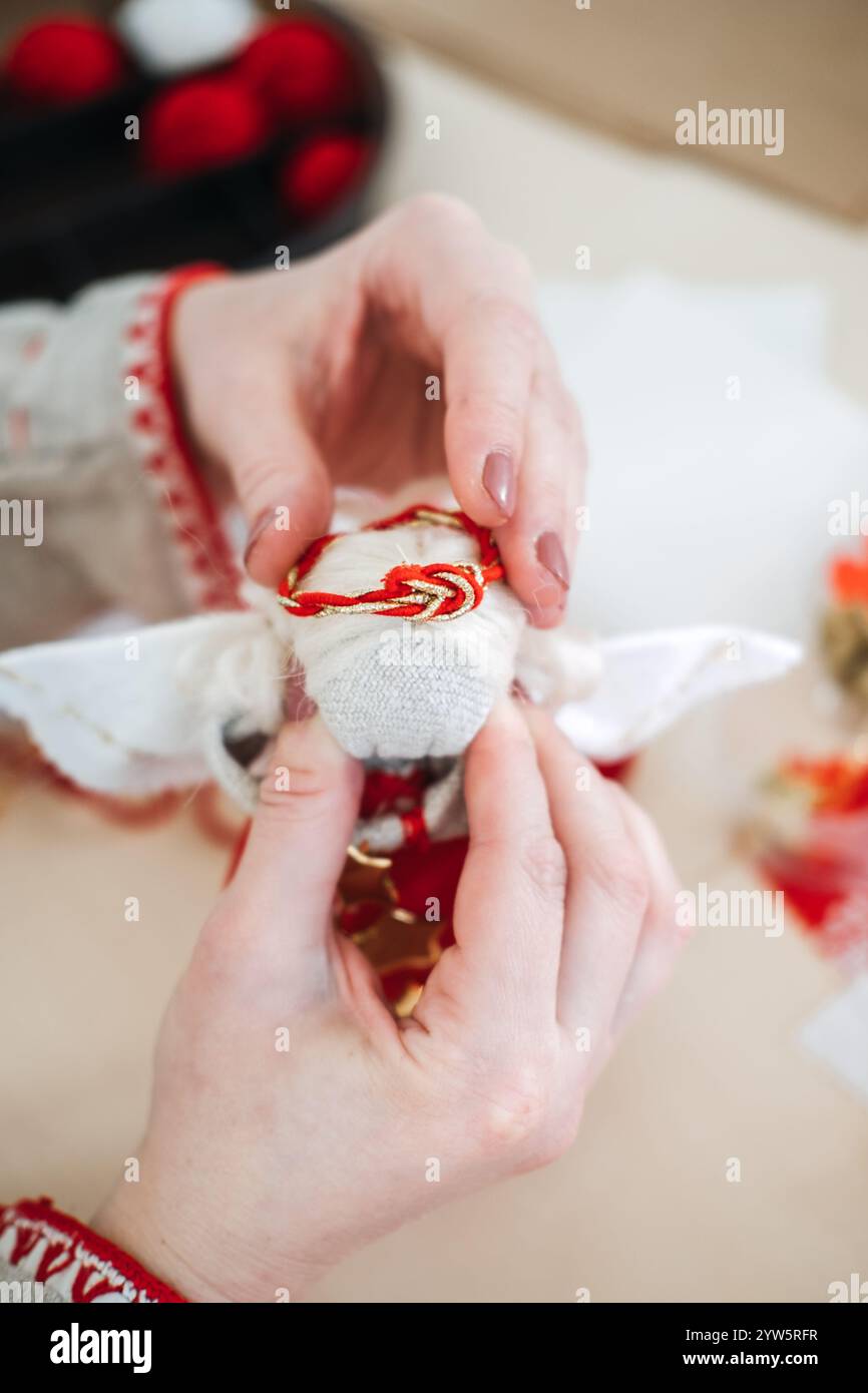 Crafting traditional folk doll with red and gold accents. Showcasing ...