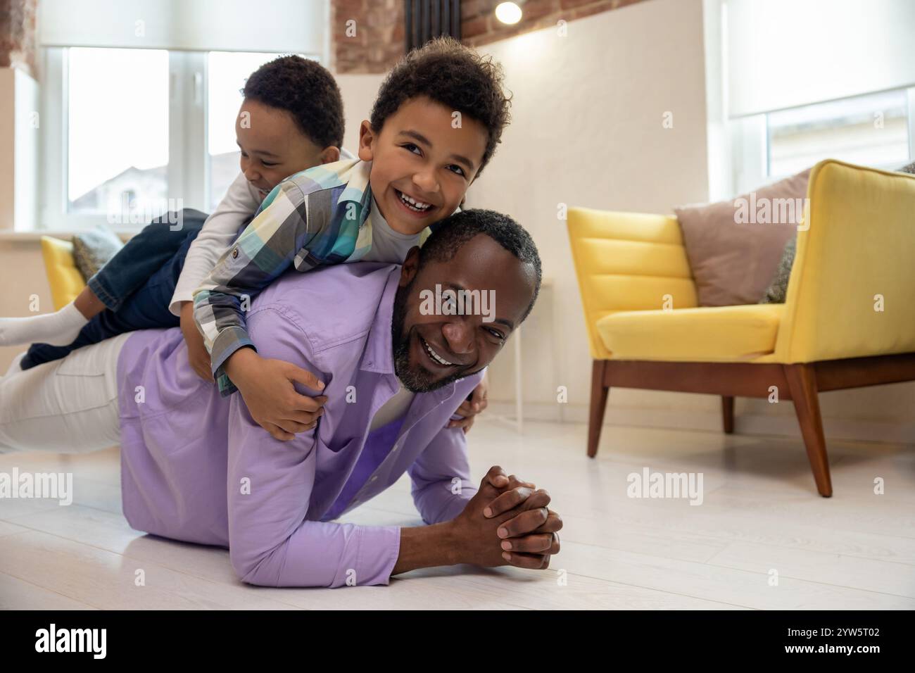 Dark-skinned father playing with his kids and carrying them on his back ...
