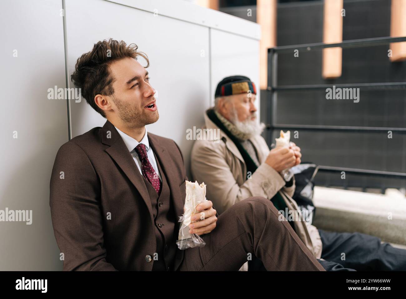 Friendly business man wearing suit and tie sharing sandwich with ...
