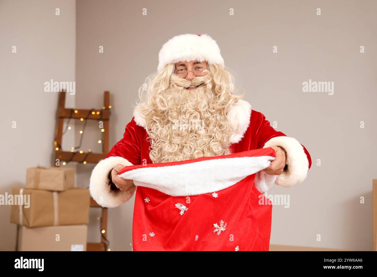 Santa Claus holding bag of gifts in living room with parcels and ...