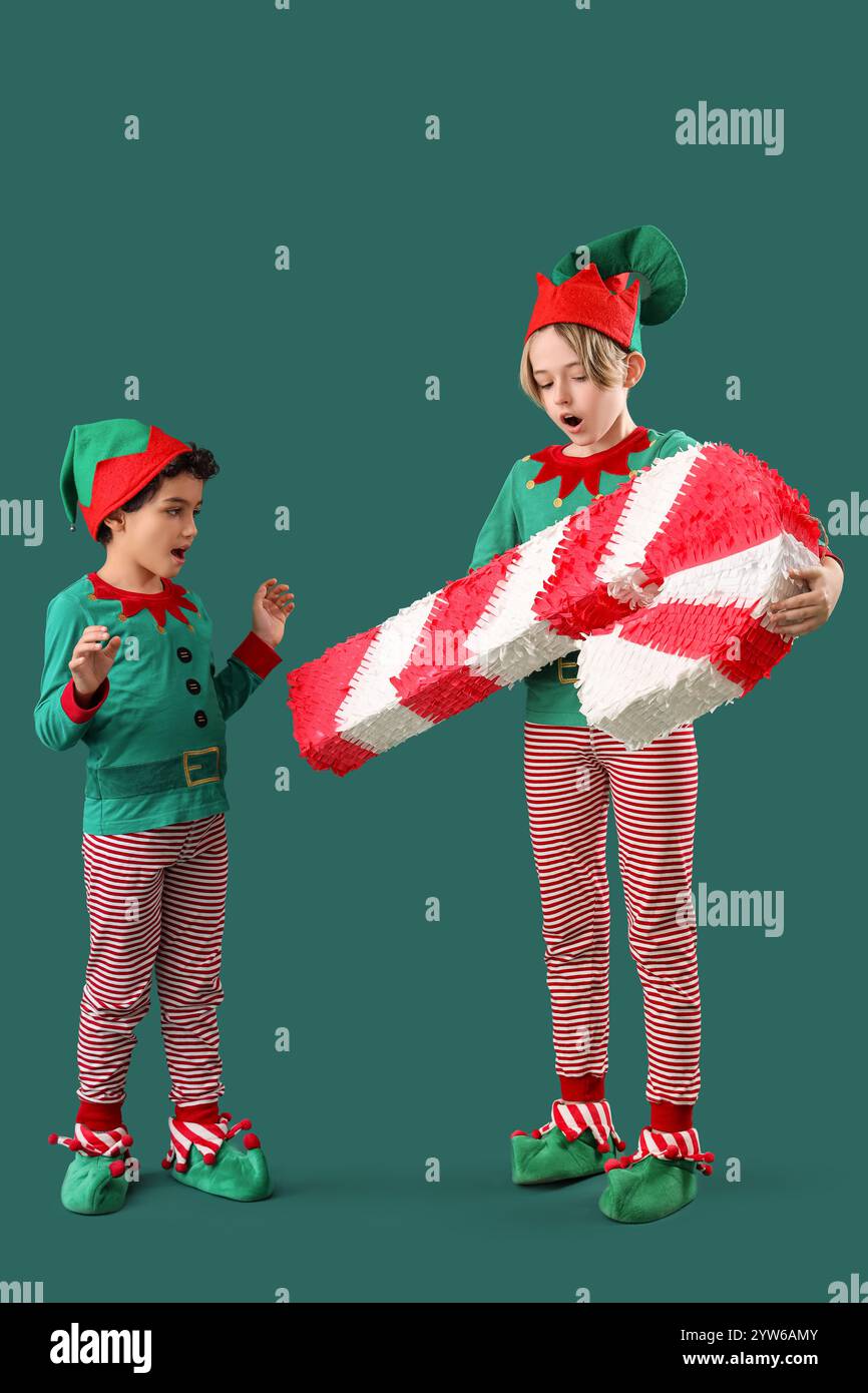 Shocked little children in elves costumes with candy cane pinata on ...