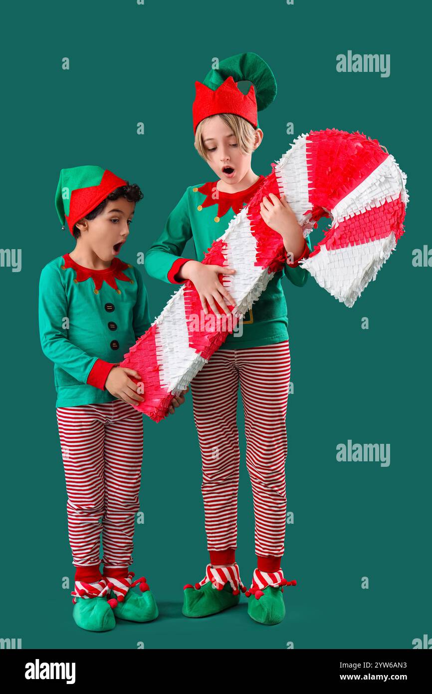 Shocked little children in elves costumes with candy cane pinata on ...