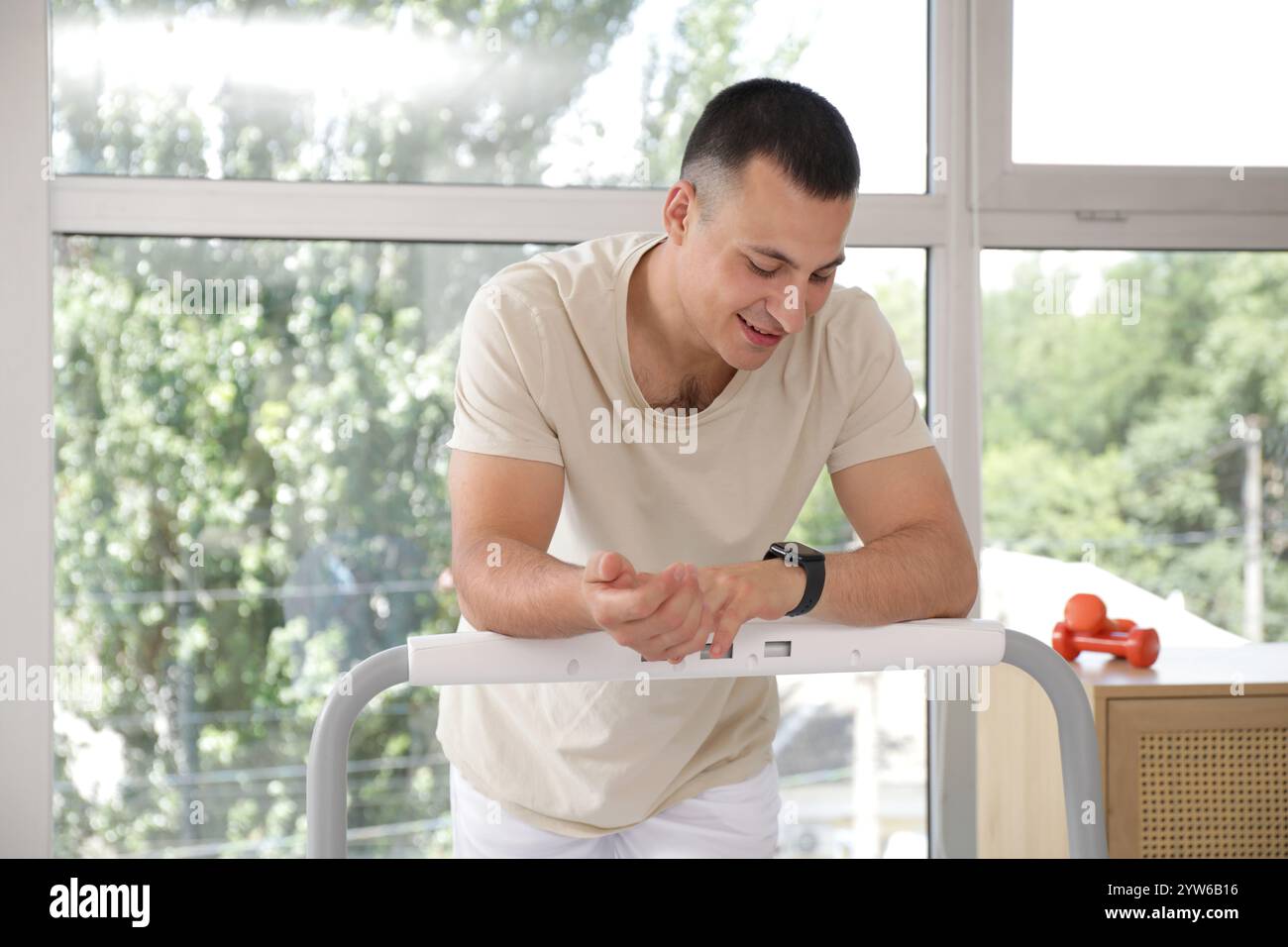 Sporty young man checking pulse on treadmill at home Stock Photo - Alamy