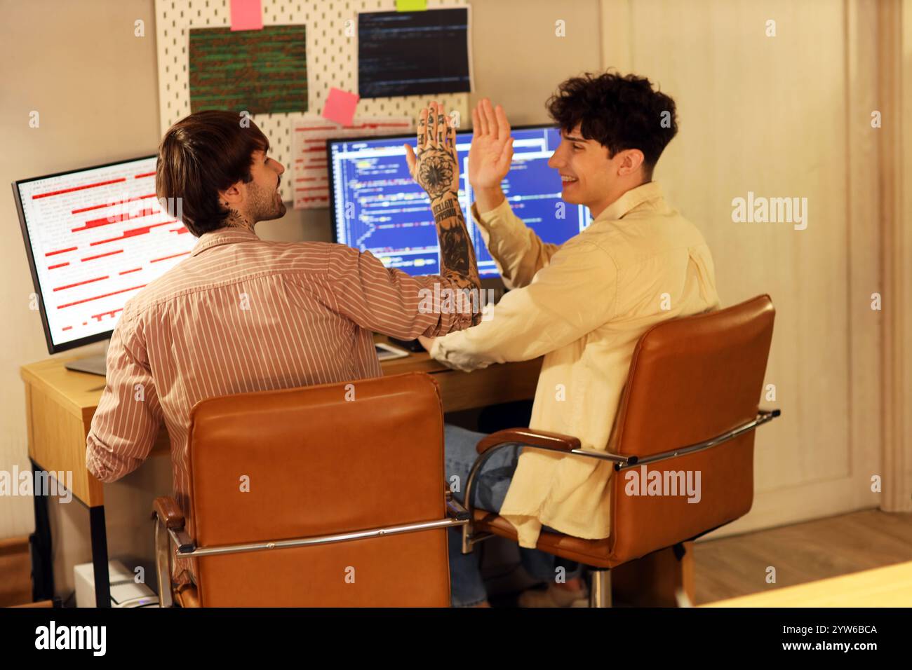 Male programmers giving each other high-five in office at night, back view Stock Photo - Alamy