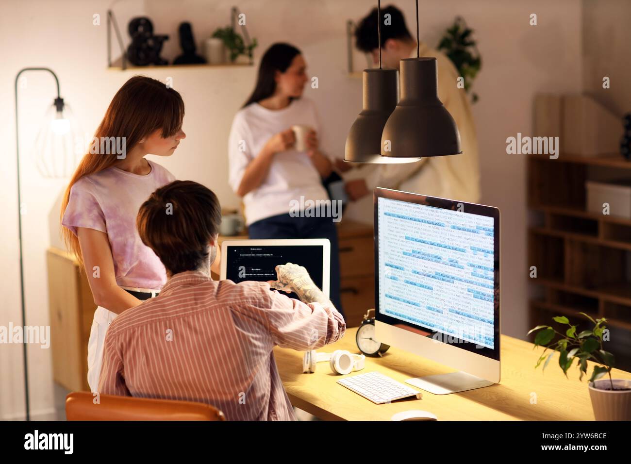 Young programmers working with laptop in office at night, back view ...
