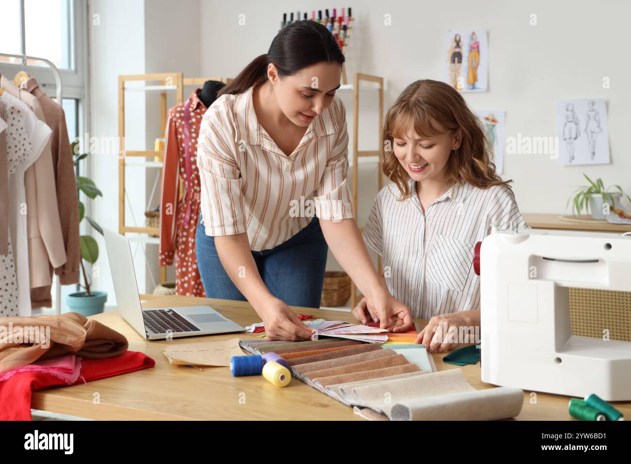Female tailors working with color palettes and fabric samples at table ...