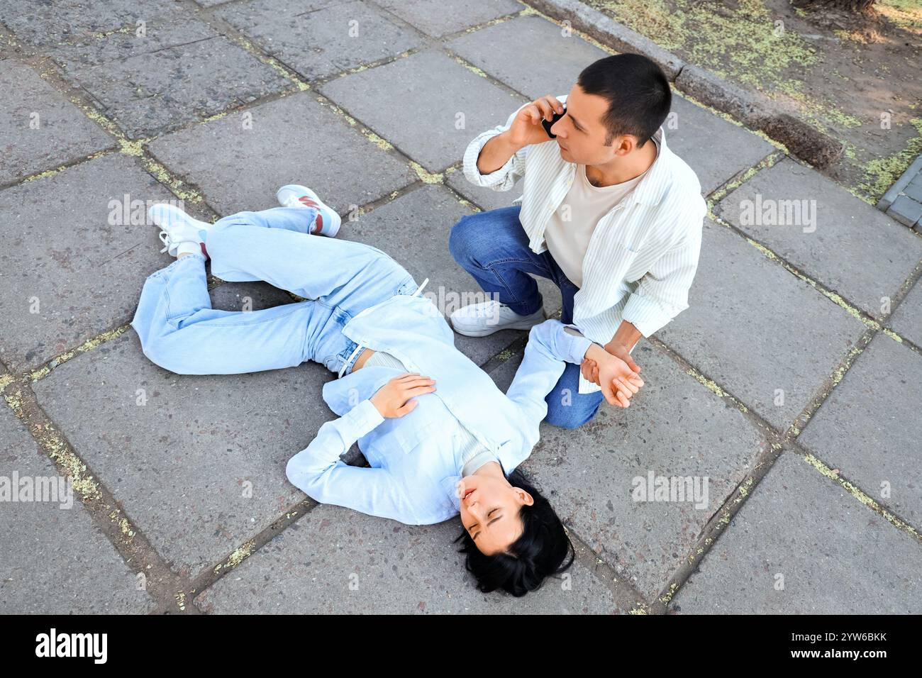Young man calling ambulance for his wife having heart attack on street ...