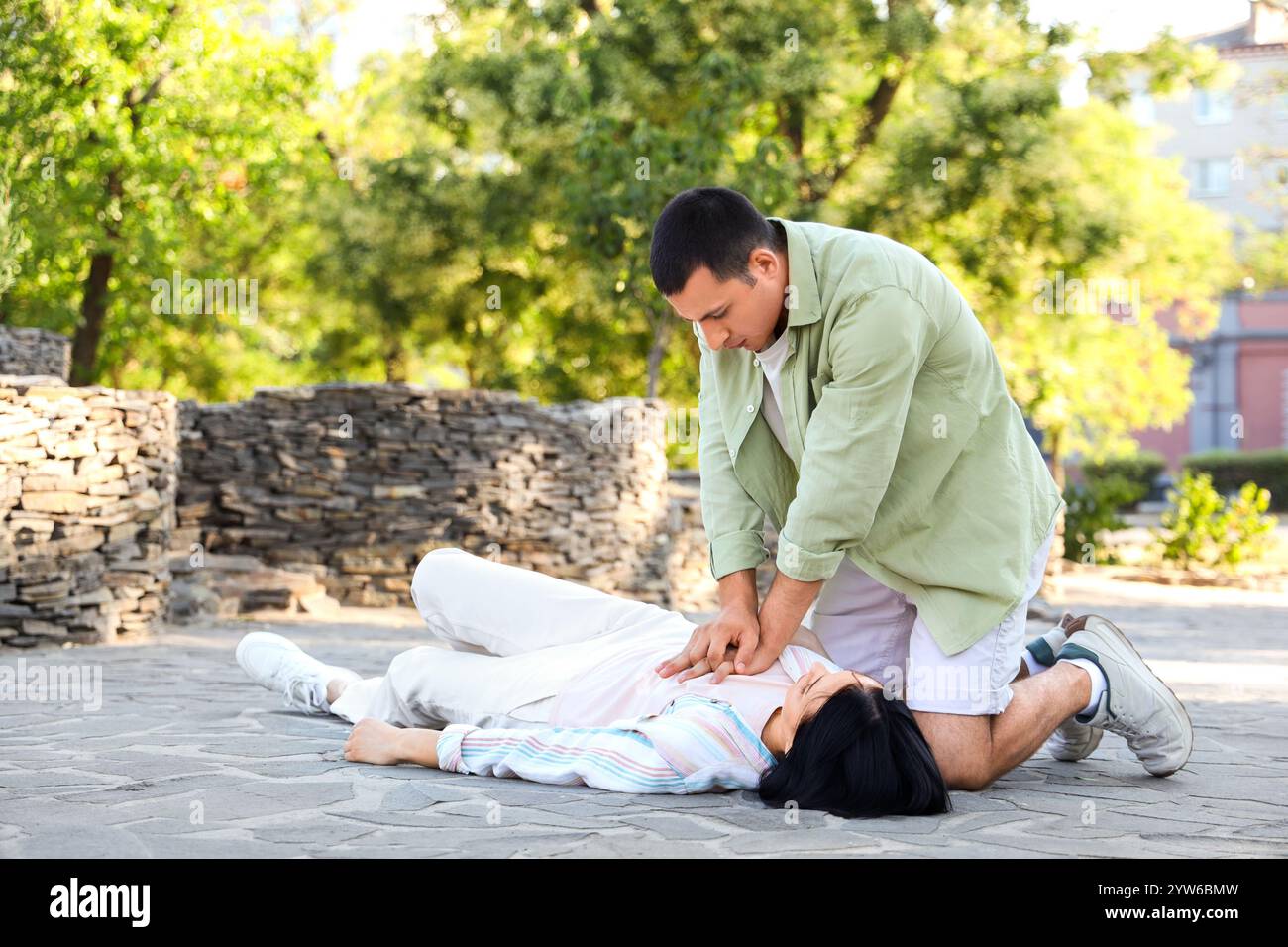 Young man doing CPR on unconscious woman having heart attack on street ...