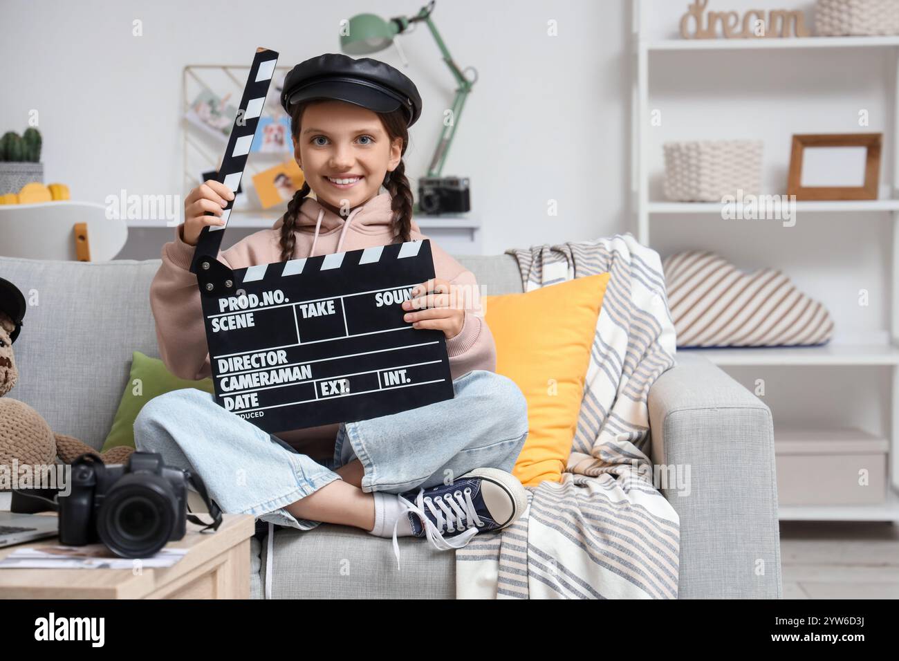 Cute girl with movie clapper sitting on sofa at home Stock Photo - Alamy