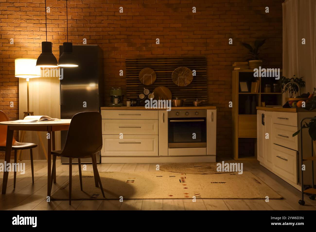 Interior of dark kitchen with counters, dining table and glowing lamps ...