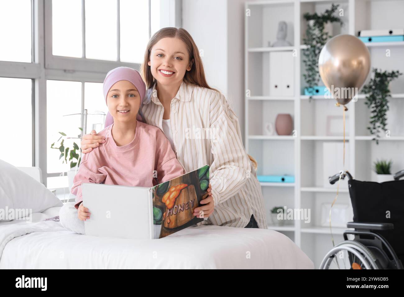 Little girl after chemotherapy with mother reading book at hospital ...