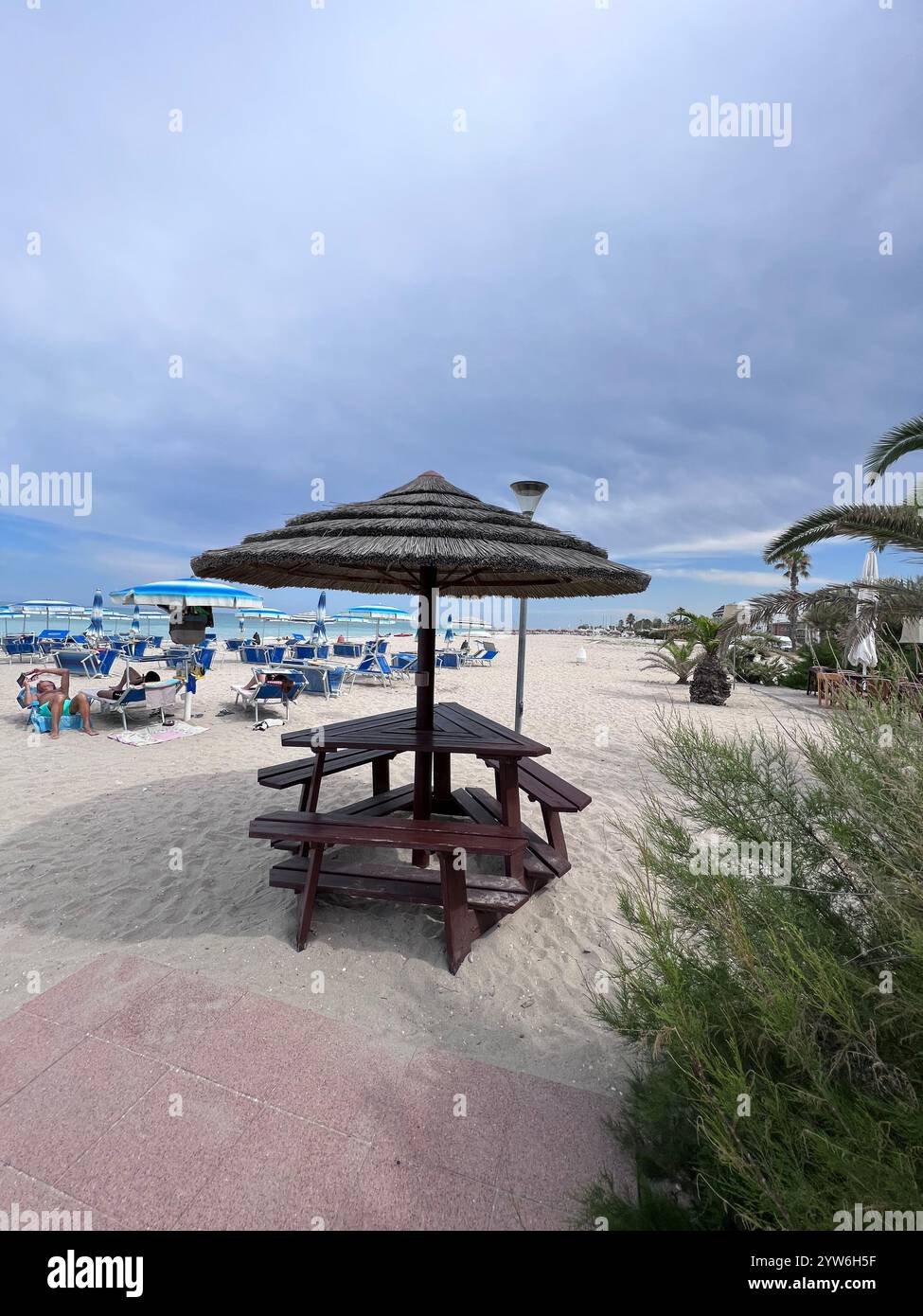 A tranquil beach setting featuring a wooden picnic table under a ...