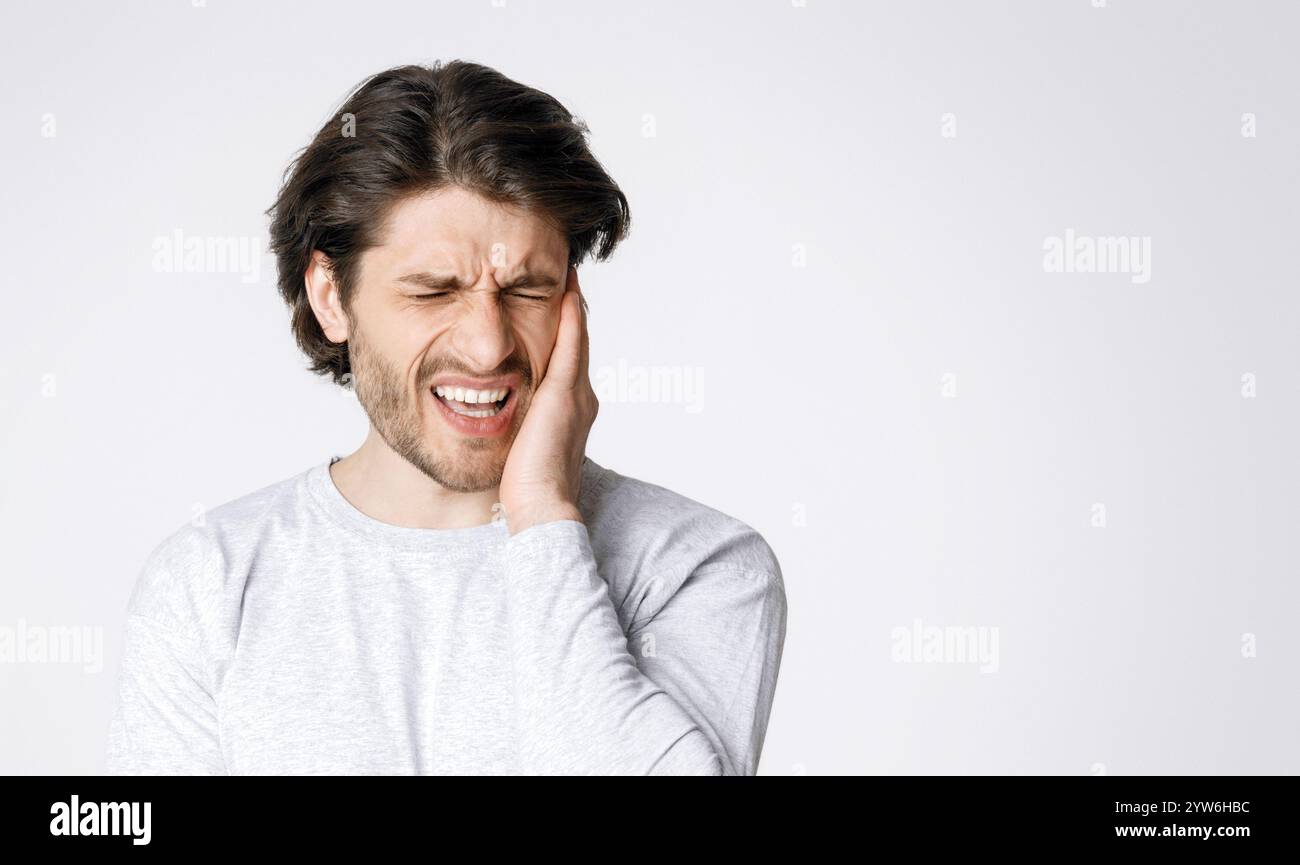 Sharp pain in ears. Man grimaces and holds his hand to sore spot Stock ...