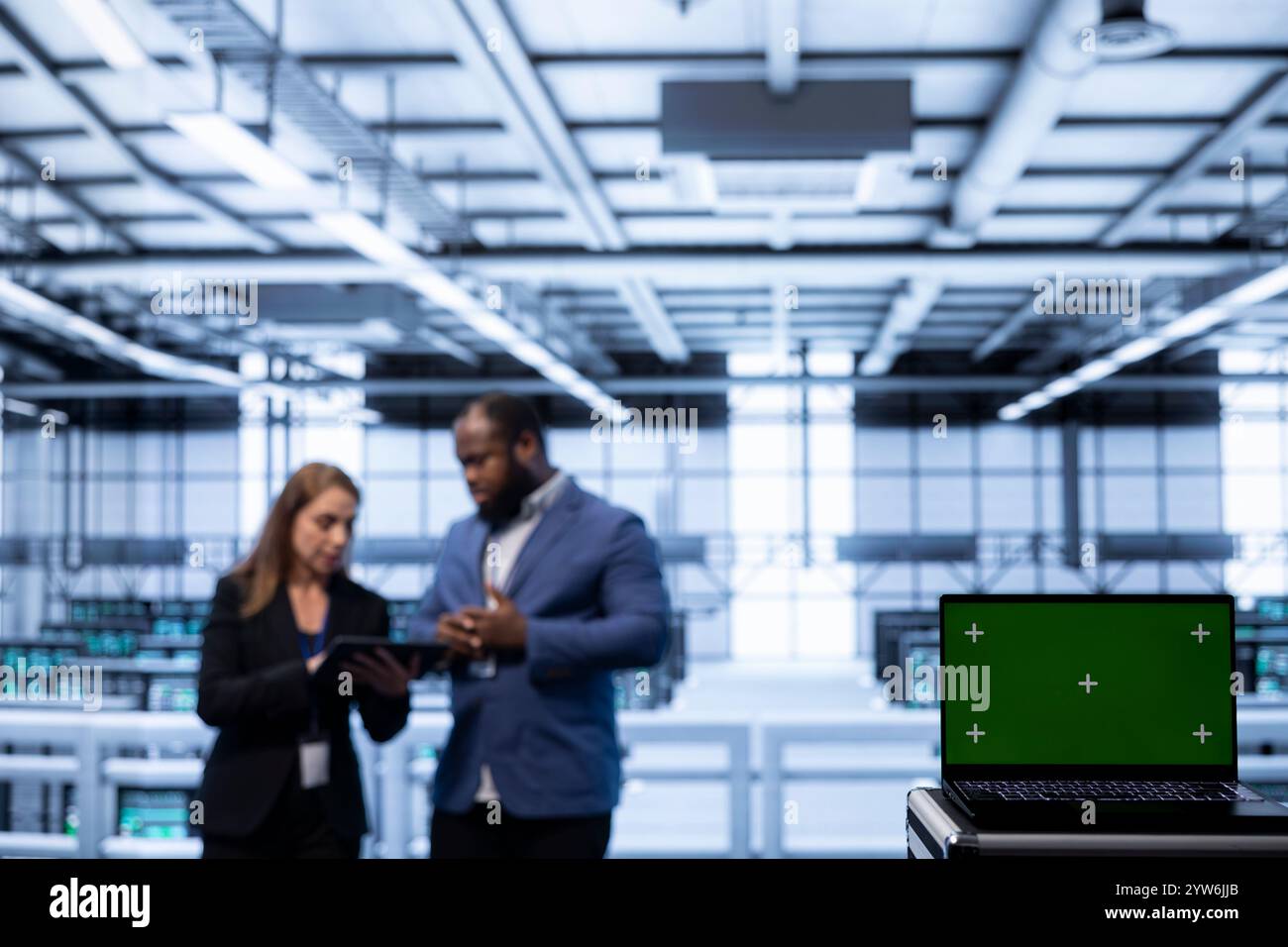 Focus on mockup laptop used by coworkers in data center ensuring cybersecurity and efficient ...