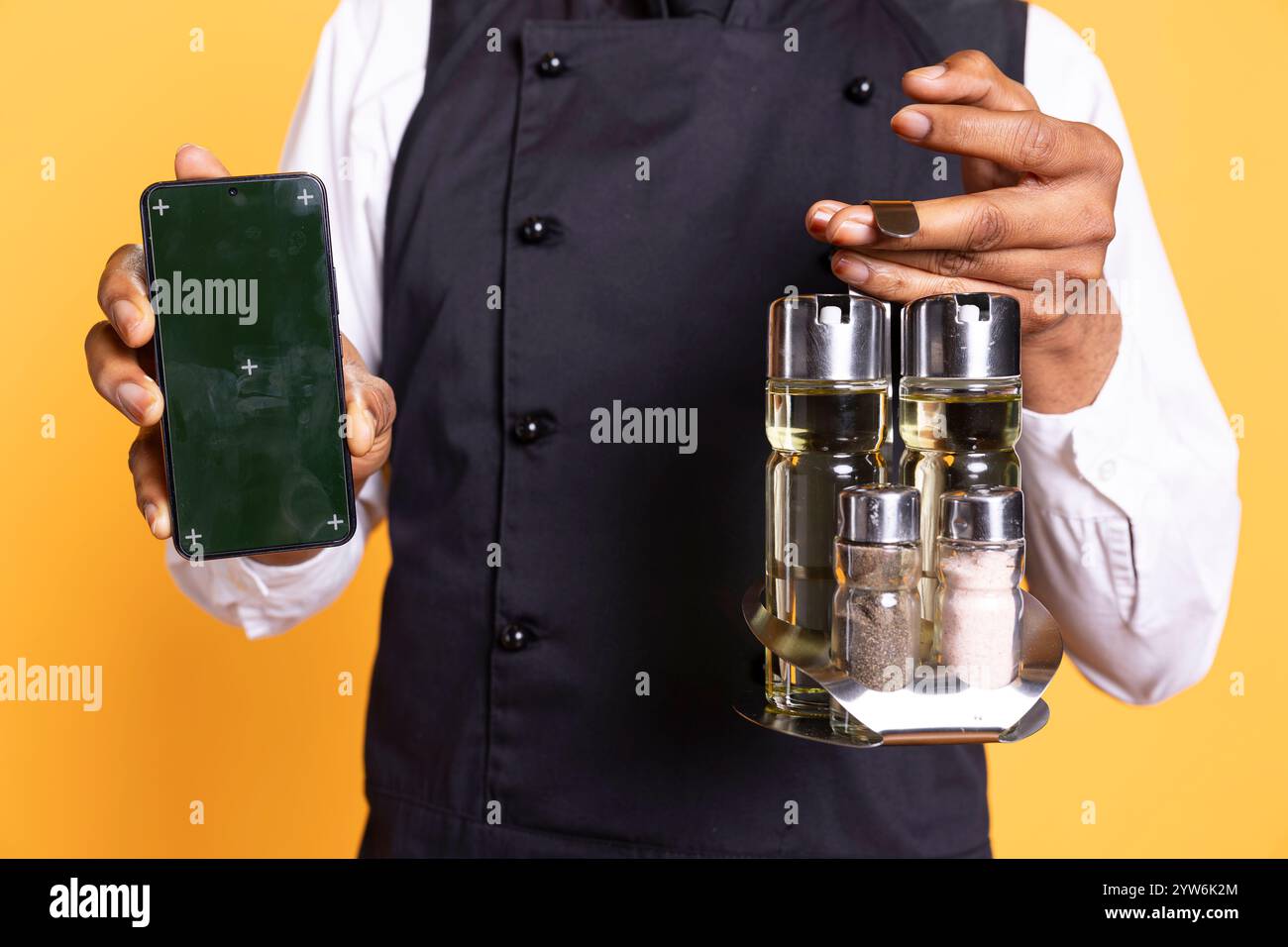 Young butler carrying a cruet set and phone with copy space display ...