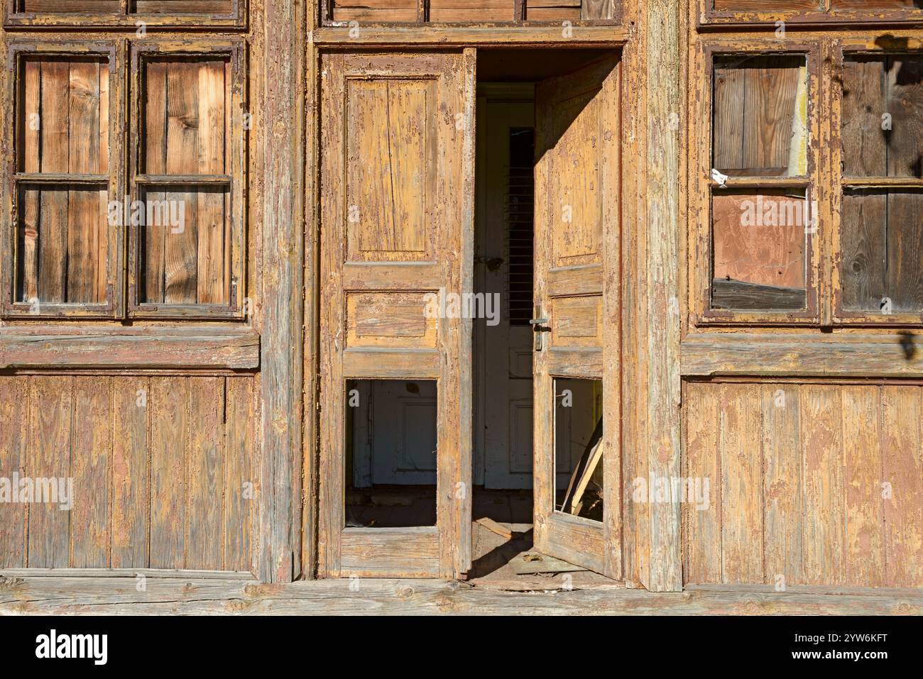 Closeup view of ajar entrance door of run-down building with faded ...