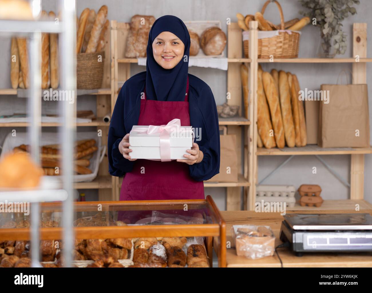 Asian Muslim woman bakery worker sells products in box, stand at ...
