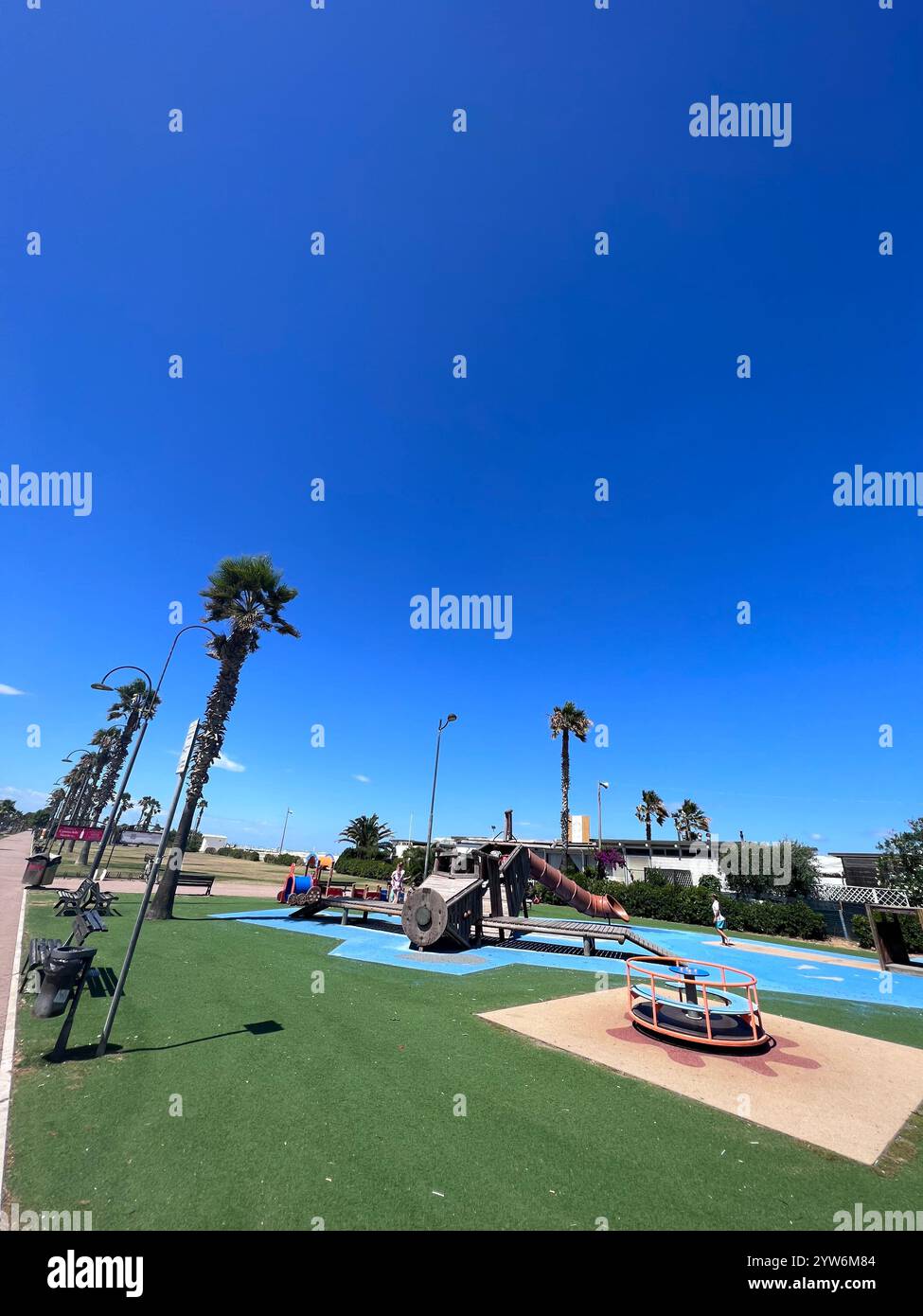 A vibrant playground under a clear blue sky surrounded by palm trees ...