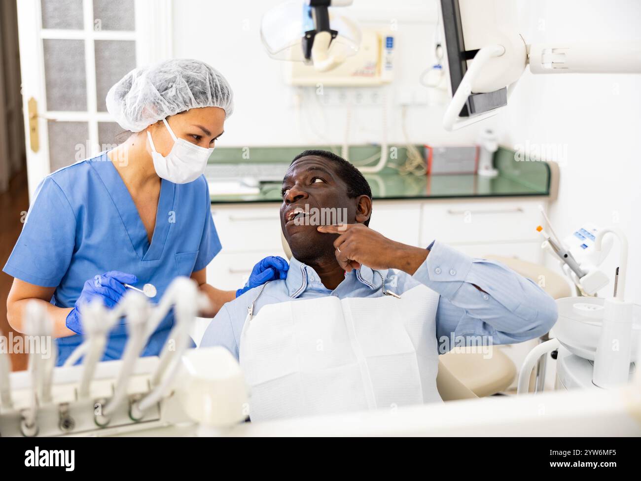 Patient pointing at tooth with problem during consultation in dental ...
