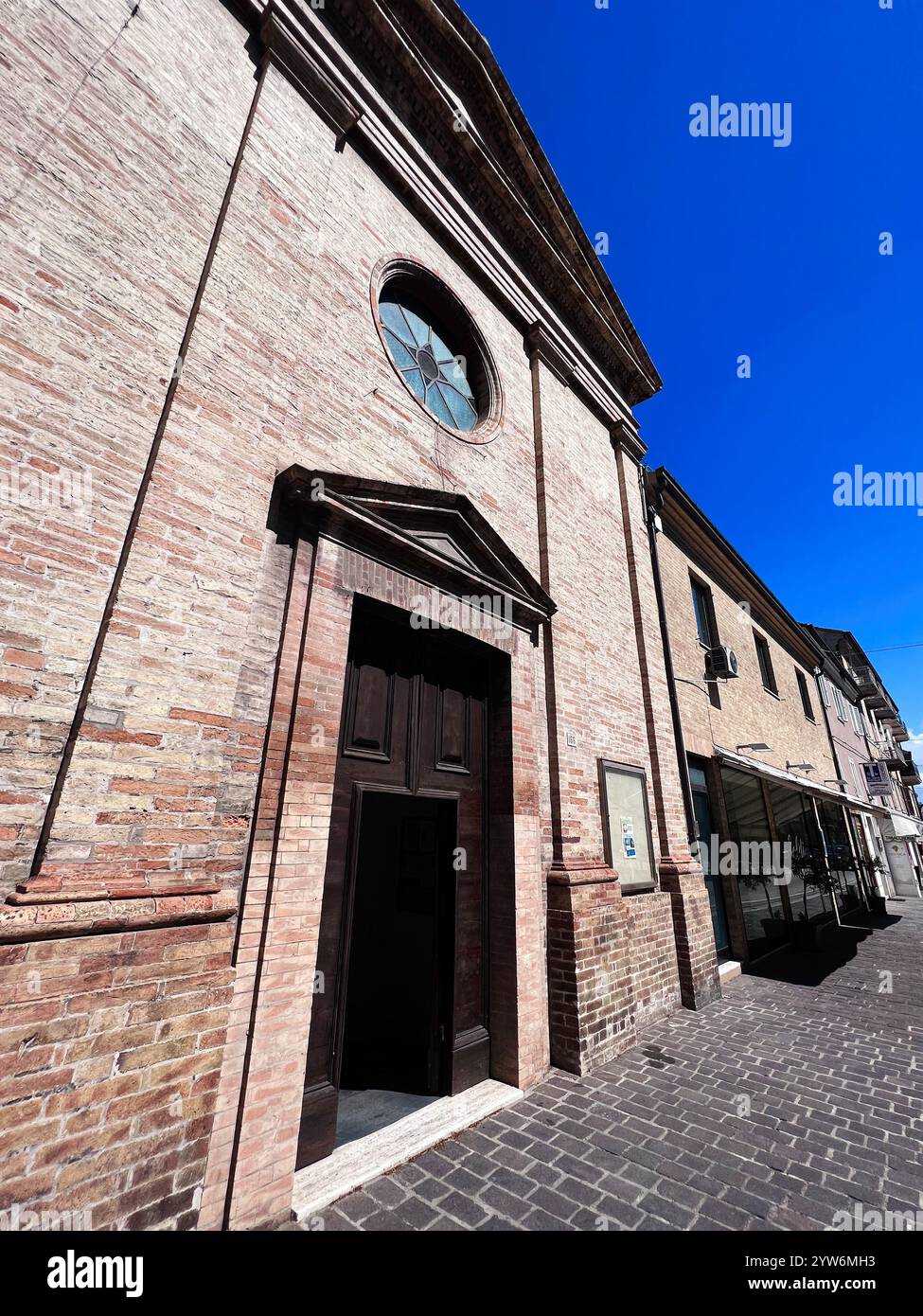 A historic brick building with a distinct circular window and open door ...
