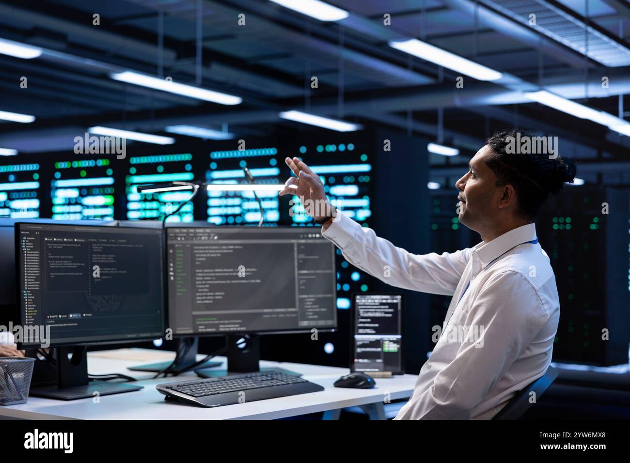 Software developer looking at holograms in data center, monitoring ...