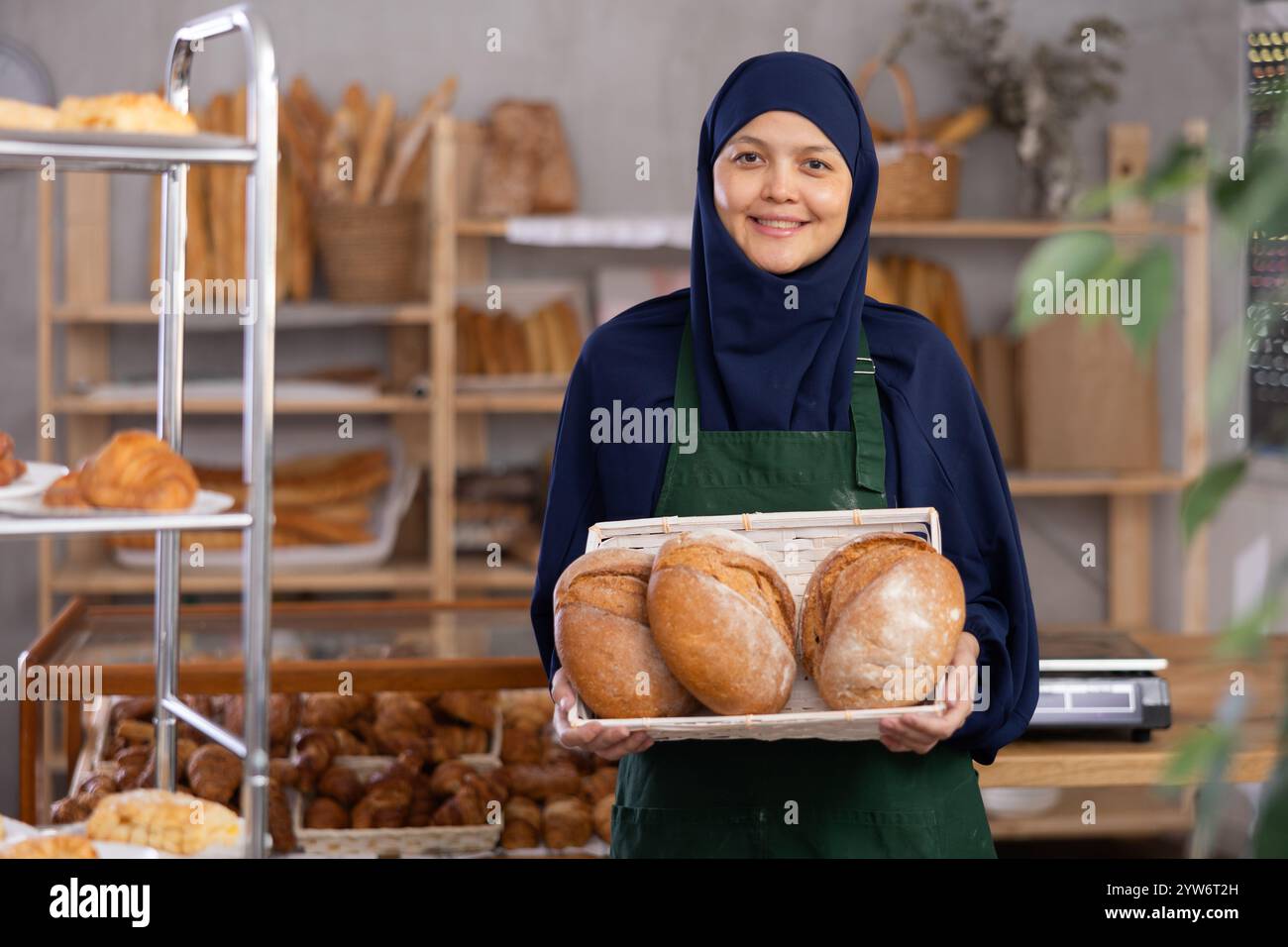 Asian Muslim woman bakery worker sells bread, stand at counter and wait ...