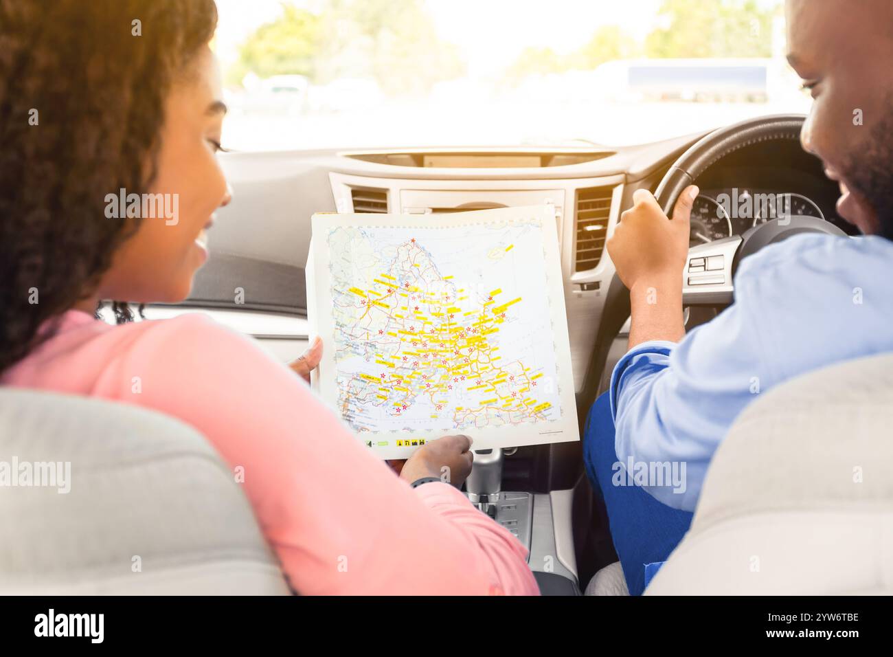 Happy black couple looking at paper map sitting inside car Stock Photo ...